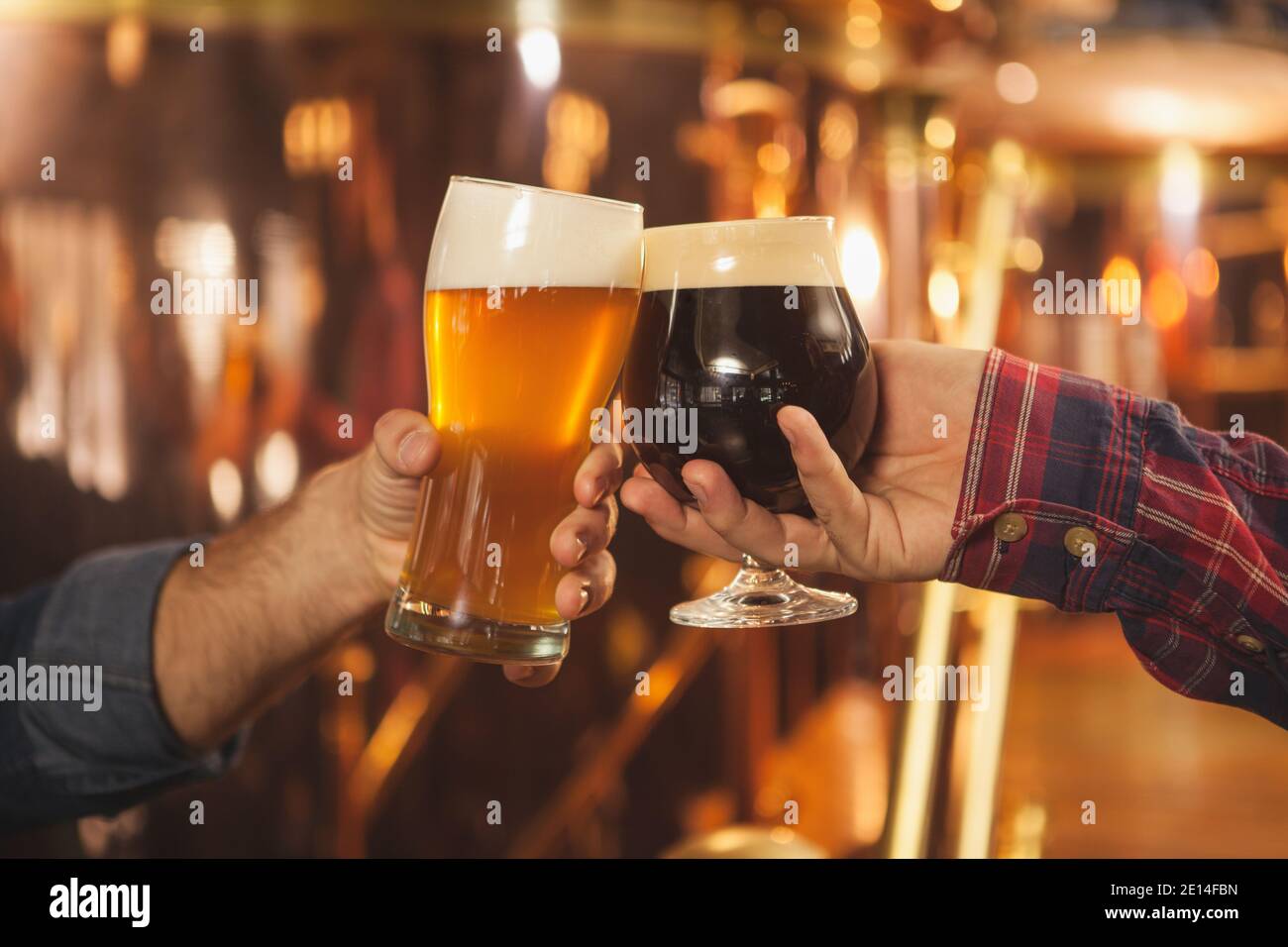 Cropped close up of two men clinking beer glasses together, celebrating ...