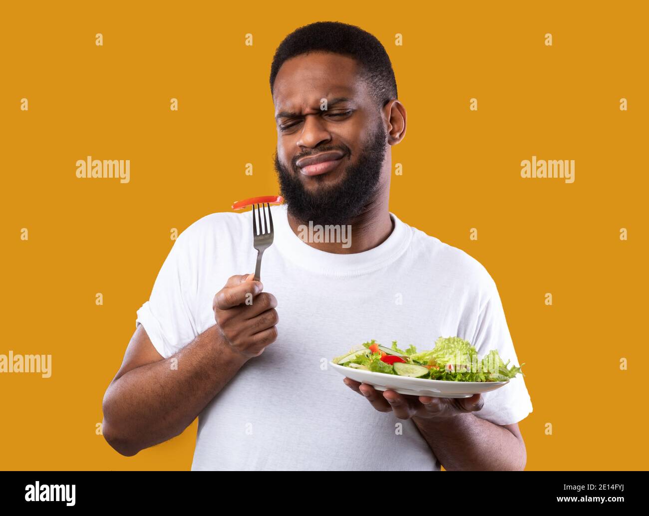 Unhappy African American Man Eating Vegetable Salad Over Yellow ...