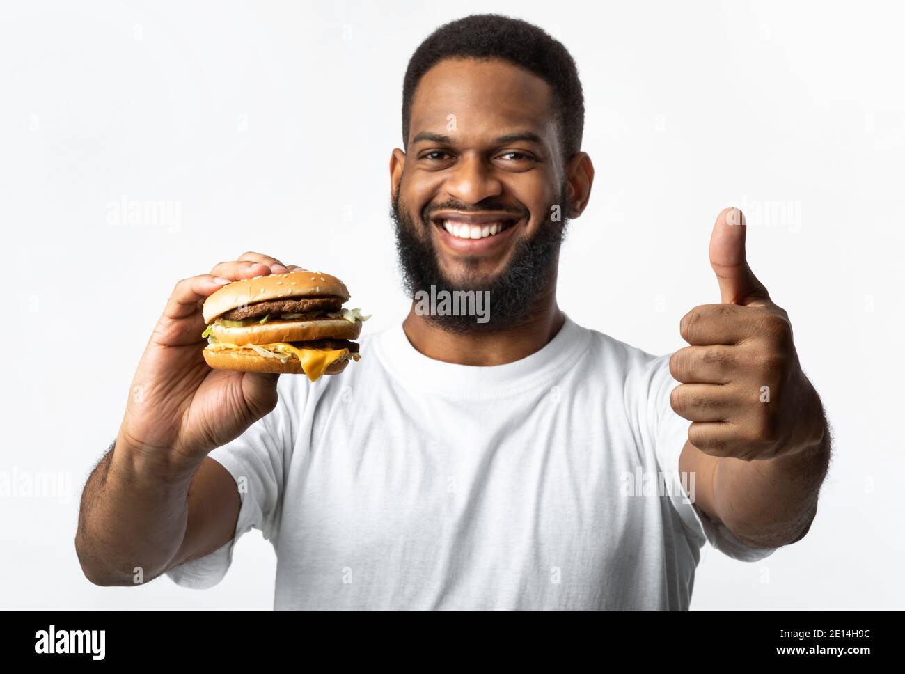 Black Man Holding Burger And Gesturing Thumbs-Up Over Yellow Background ...