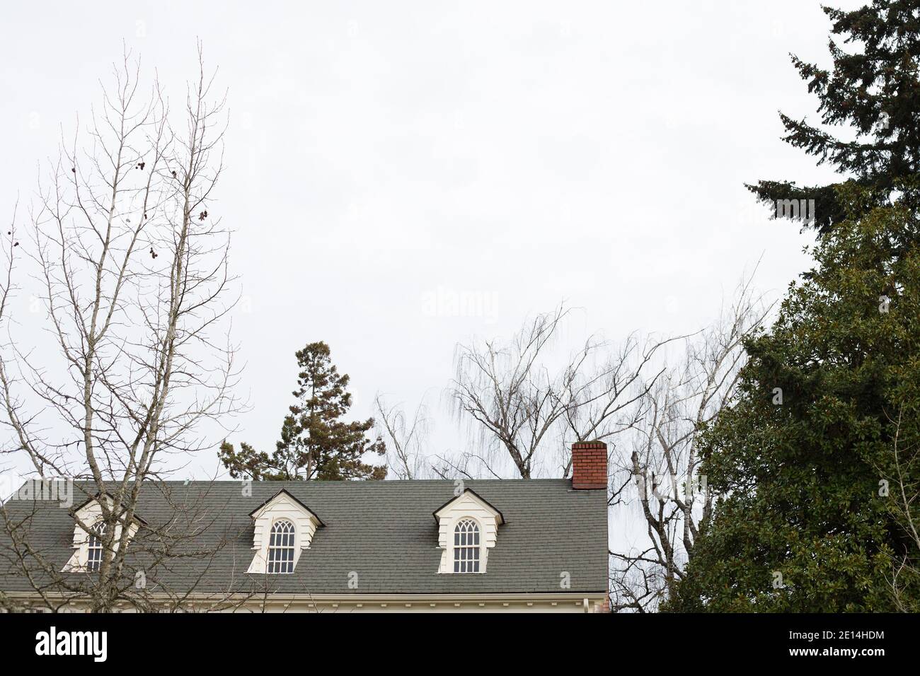The attic windows, roof and chimney of a Colonial style house ...