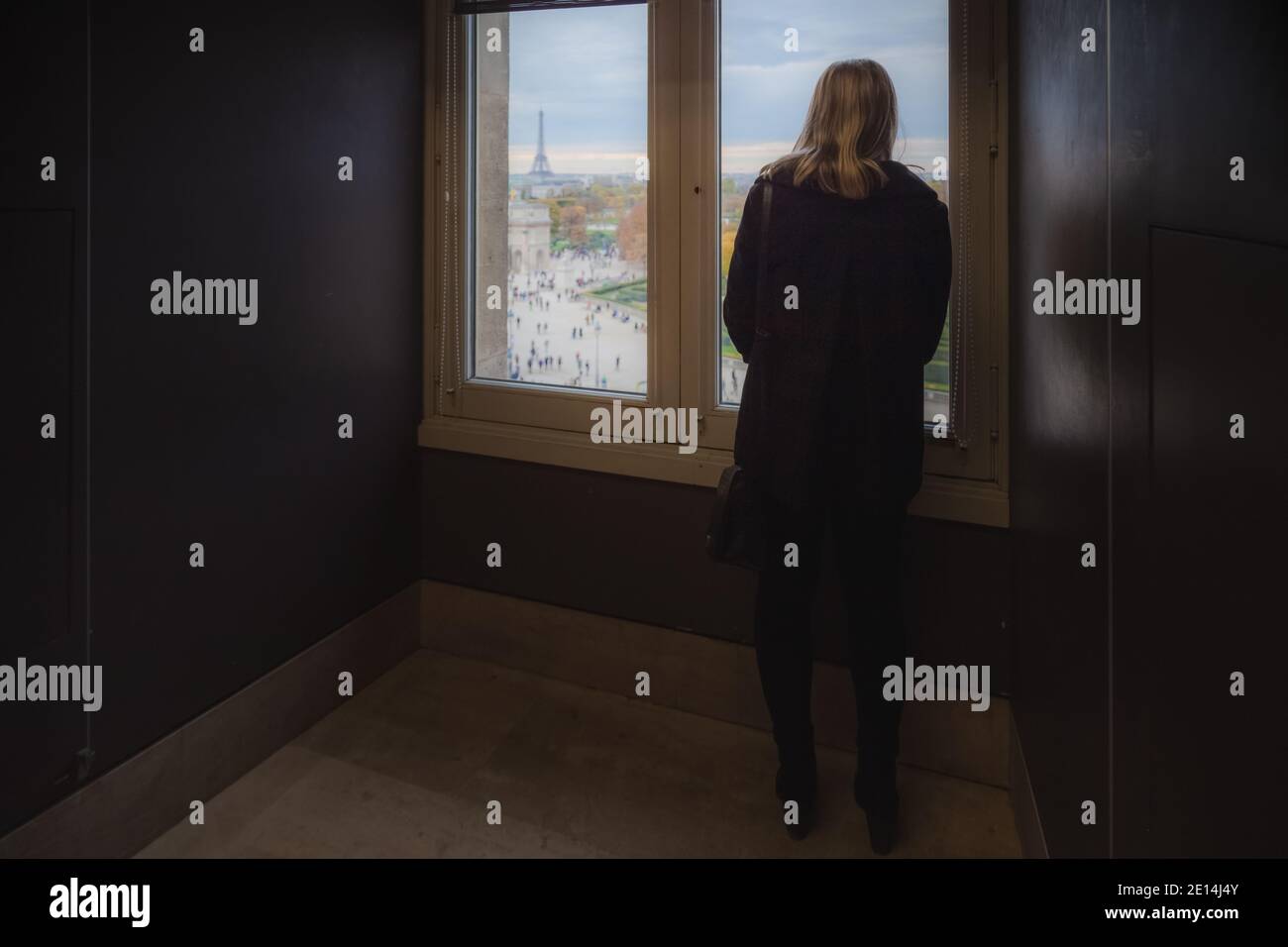 Woman peering out of window hi-res stock photography and images - Alamy