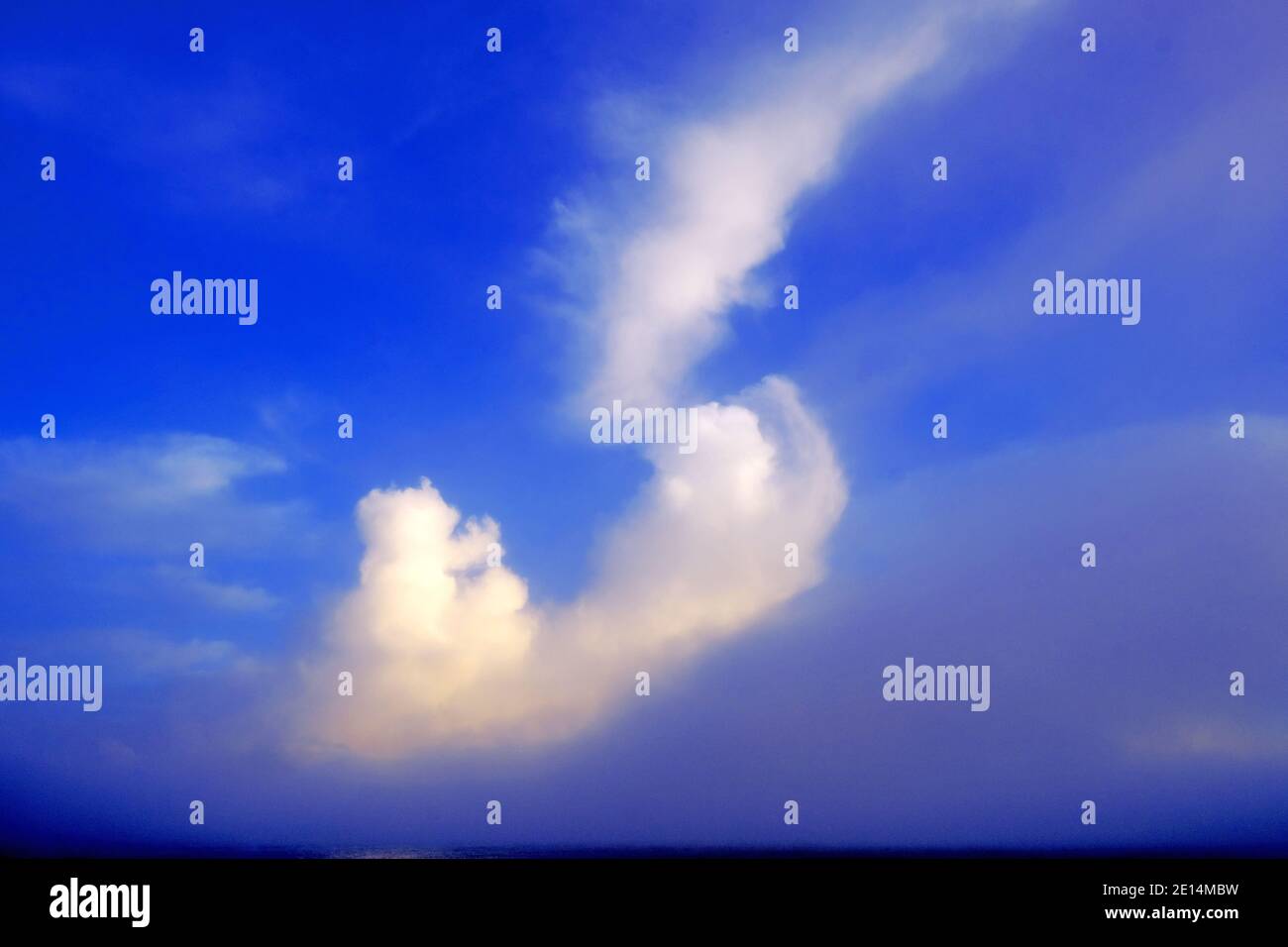 Diagonal cloud seascape against blue sky with light reflecting on the ...