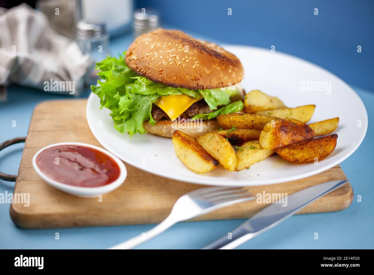 Homemade imperfect burger with potatoes and salad on a plate. Food on ...
