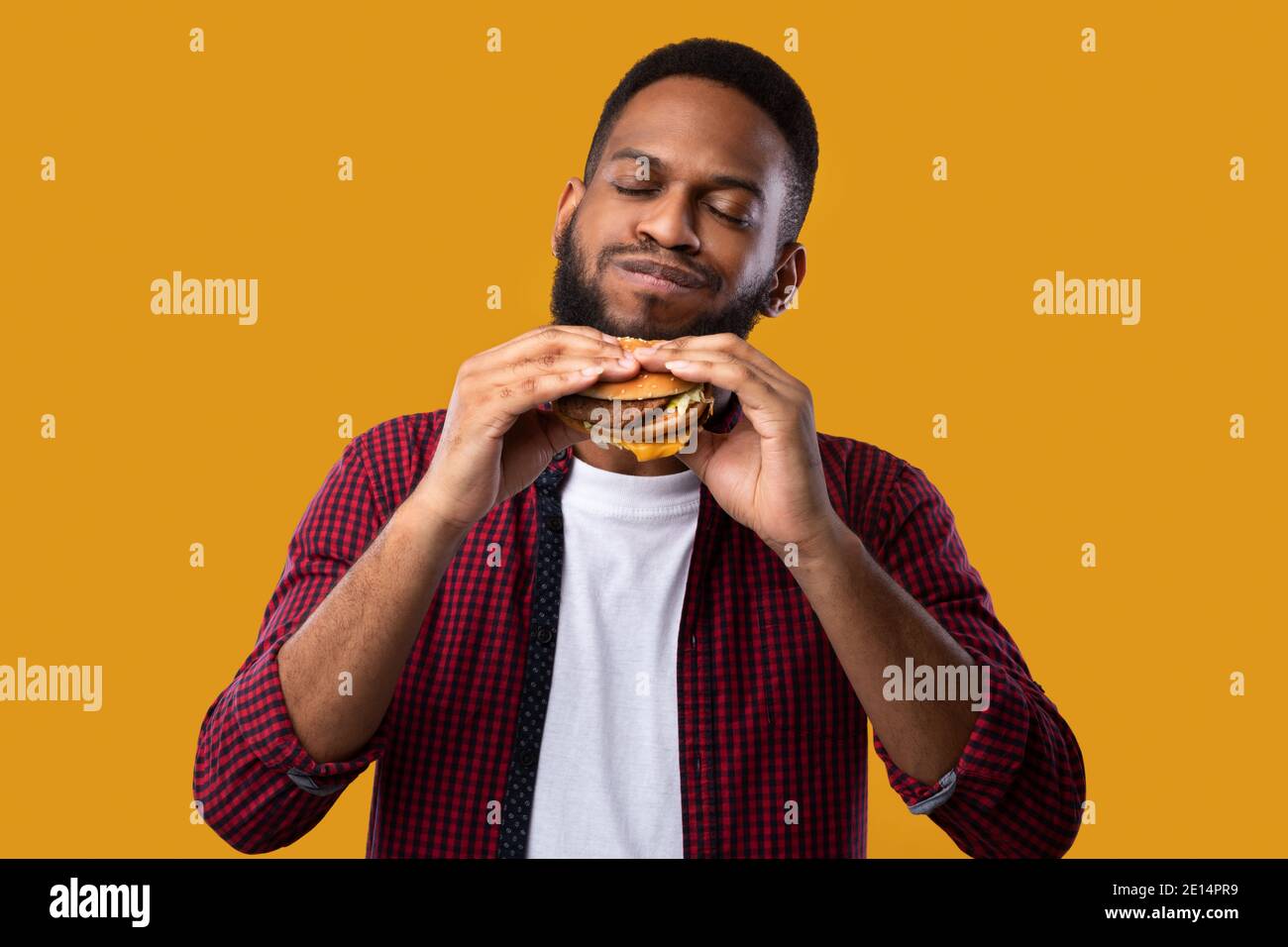 Happy African Man Eating Burger Posing Over Yellow Studio Background ...