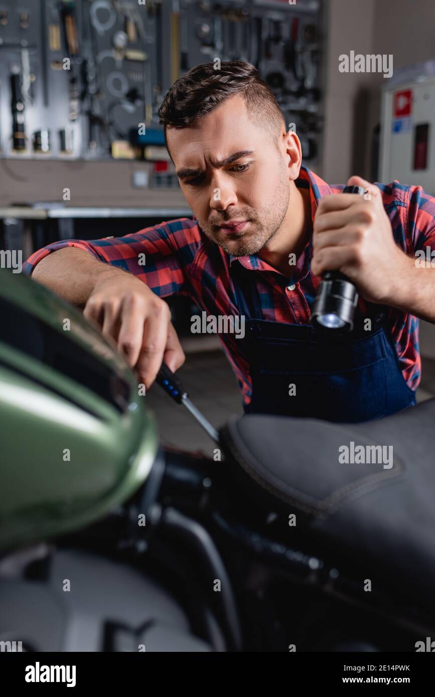 mechanic using flashlight and screwdriver during diagnostics of ...