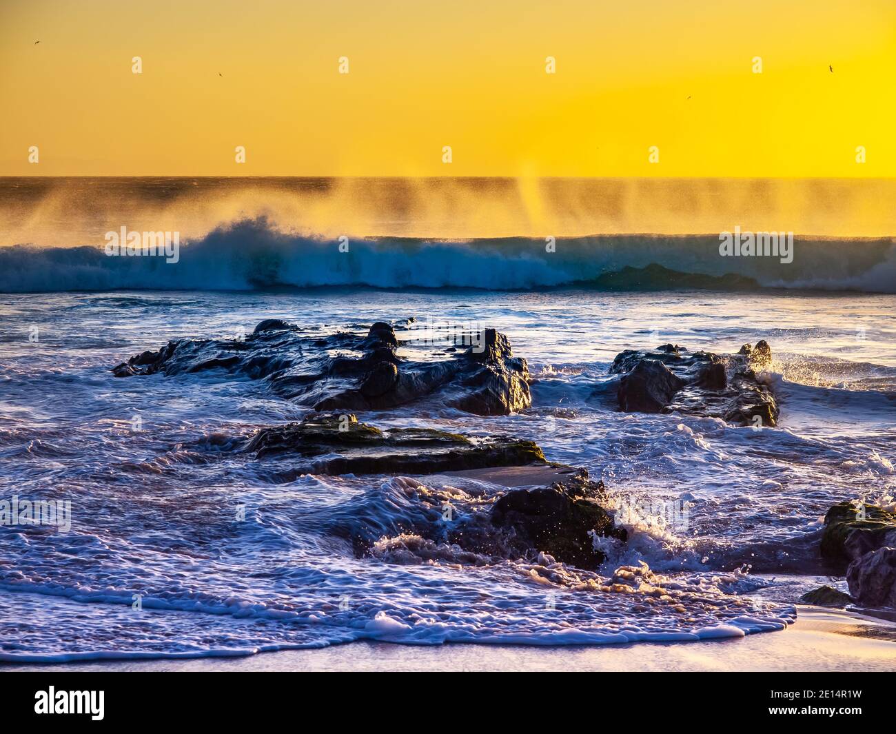 Waves Crashing Onto Rocks During A Storm On The Beach During Sunset ...