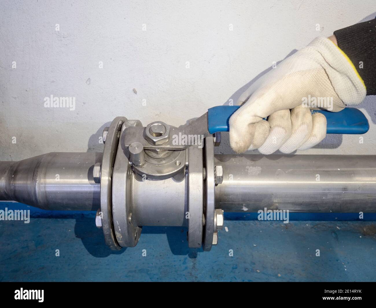 Worker's hand with safety glove opened manualy ball valve on silver ...