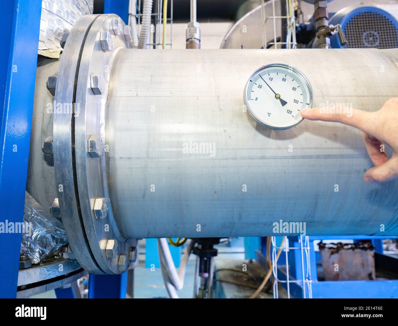 Worker pointing and showing safe tepmerature in pipe delivery system ...