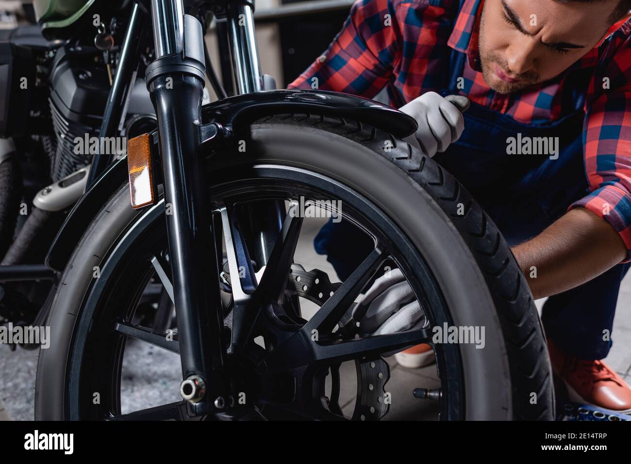 young mechanic checking wheel of motorcycle in workshop Stock Photo - Alamy