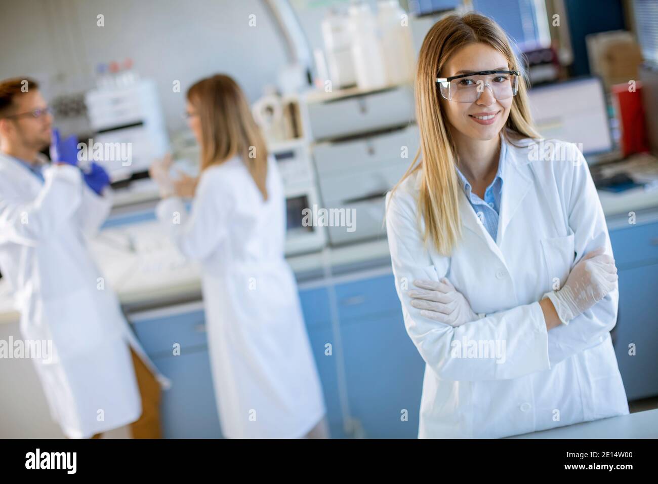 Young female scientist in white lab coat standing in the biomedical lab ...
