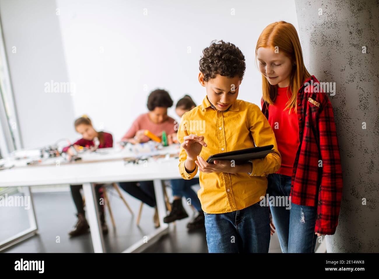 Cute little friends standing in front of group of kids programming ...
