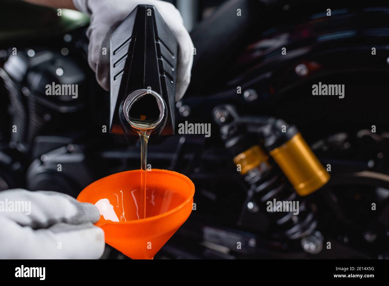 partial view of mechanic in gloves pouring engine oil from bottle into ...