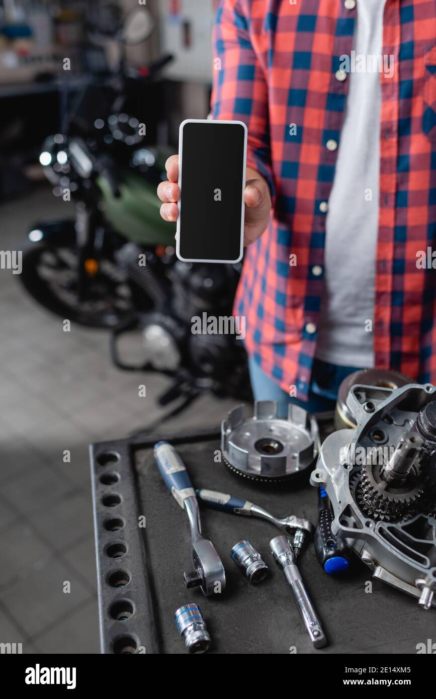 partial view of mechanic showing mobile phone with blank screen near ...