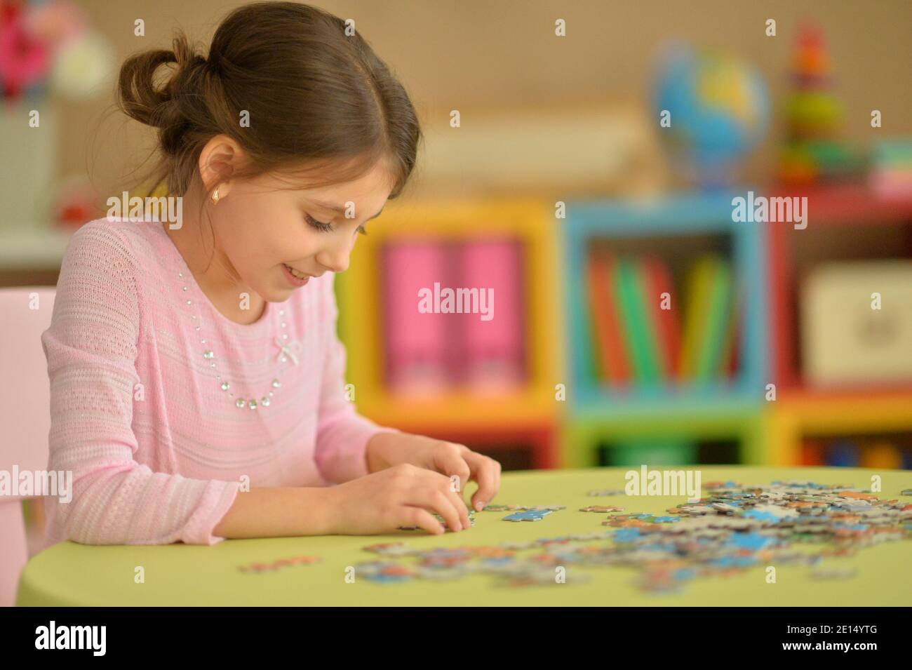 Portrait of cute little girl collecting puzzle pieces Stock Photo - Alamy