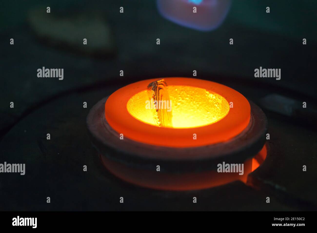 closeup picture of gold bar melting in liquid metal in furnace, glowing ...