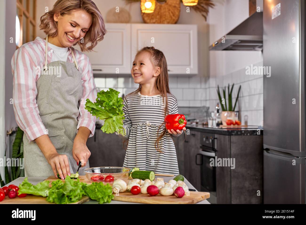 attractive young single mother making a salad in the kitchen with her ...
