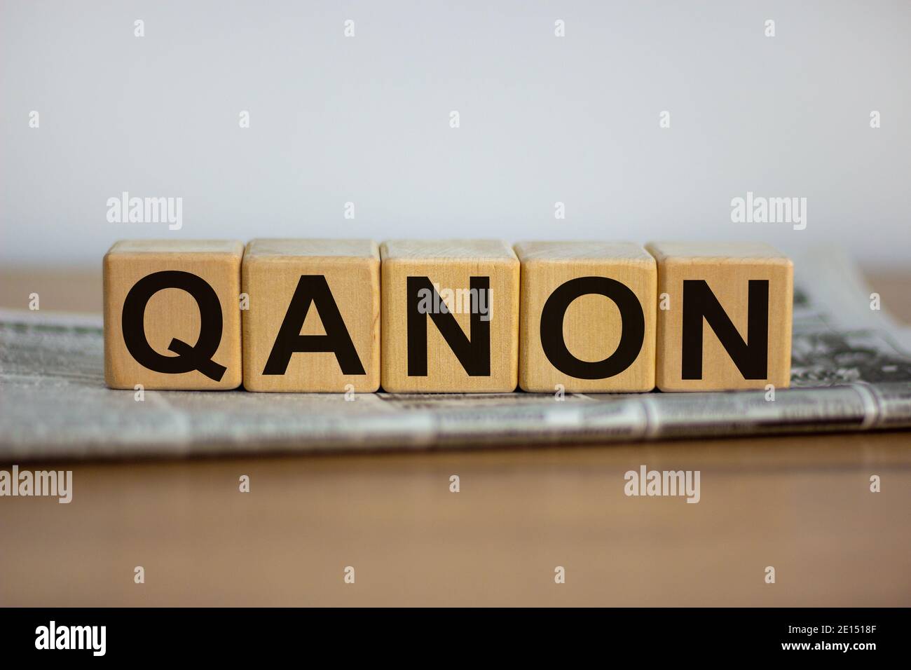 Q Anon symbol. Cubes placed on a newspaper with the word 'QANON ...