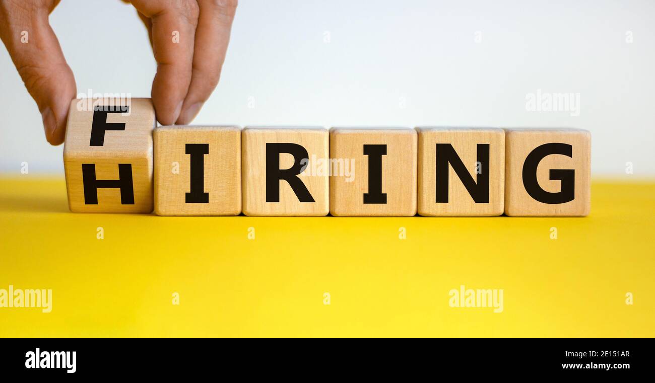 Hiring or firing symbol. Businessman hand turns a wooden cube and ... Hiring or firing symbol. Businessman hand turns a wooden cube and ...