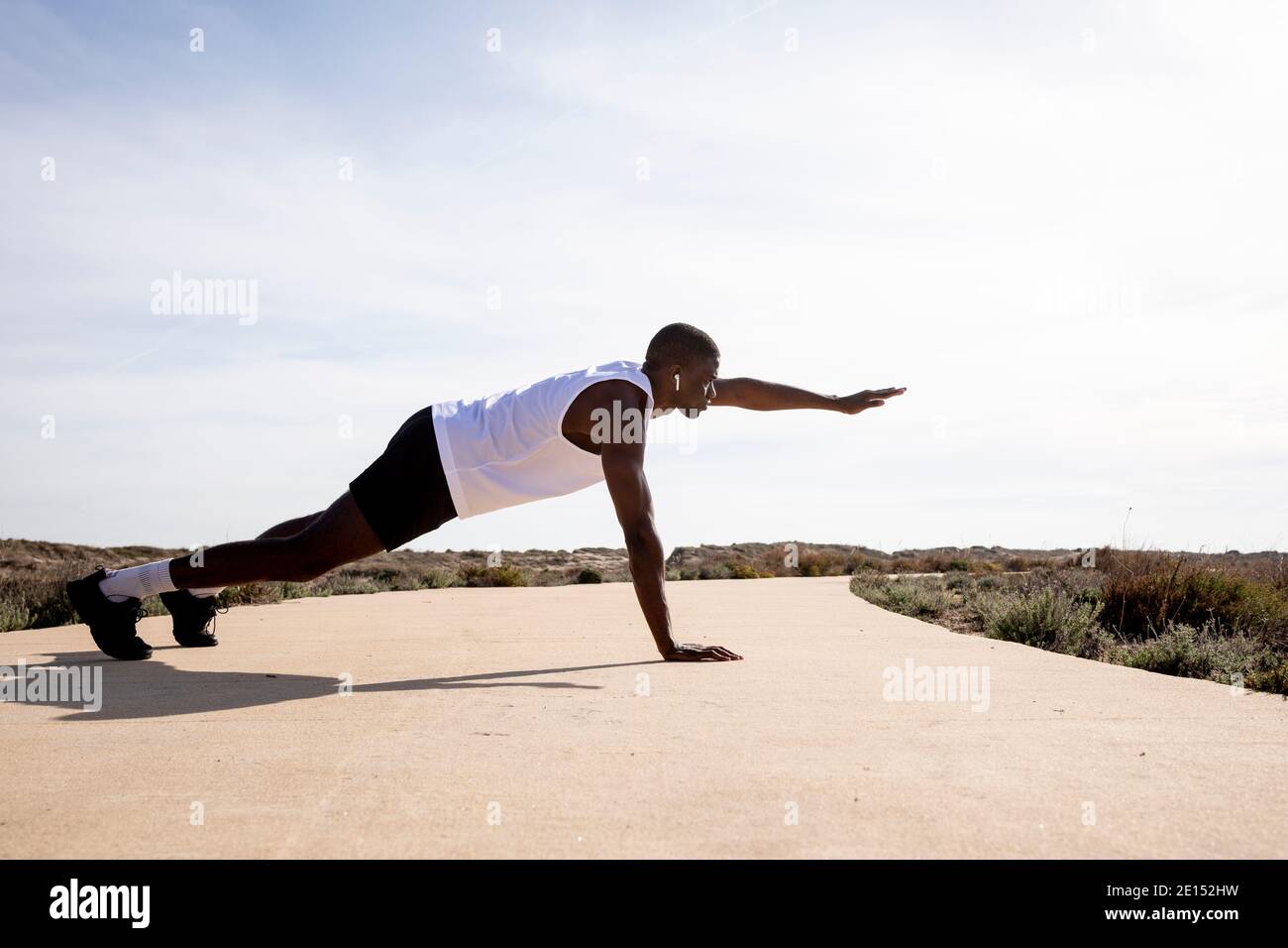 Young black runner in profile doing push-ups and lifting one arm Stock ...