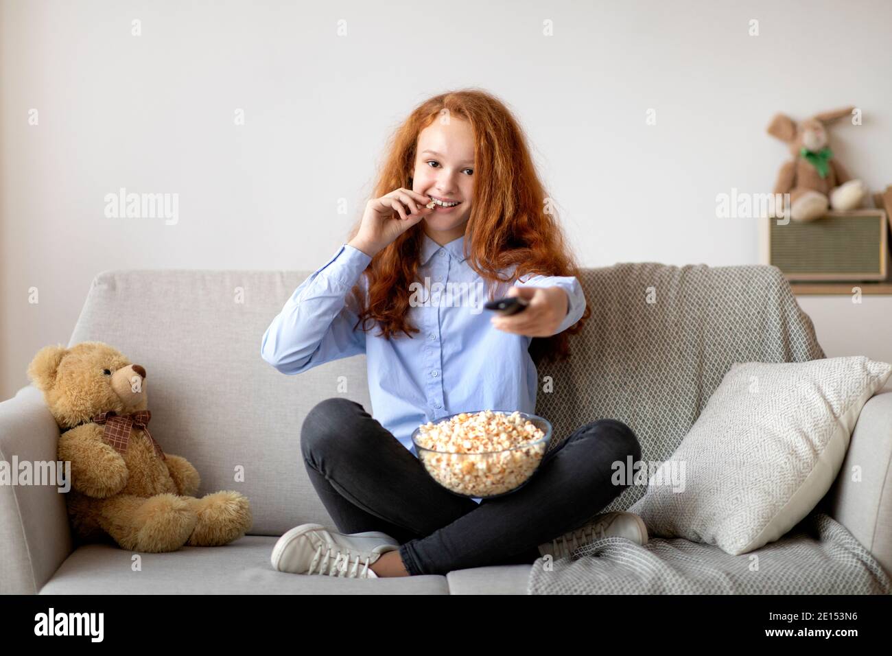 Young girl watching tv eating popcorn in her living room Stock Photo ...