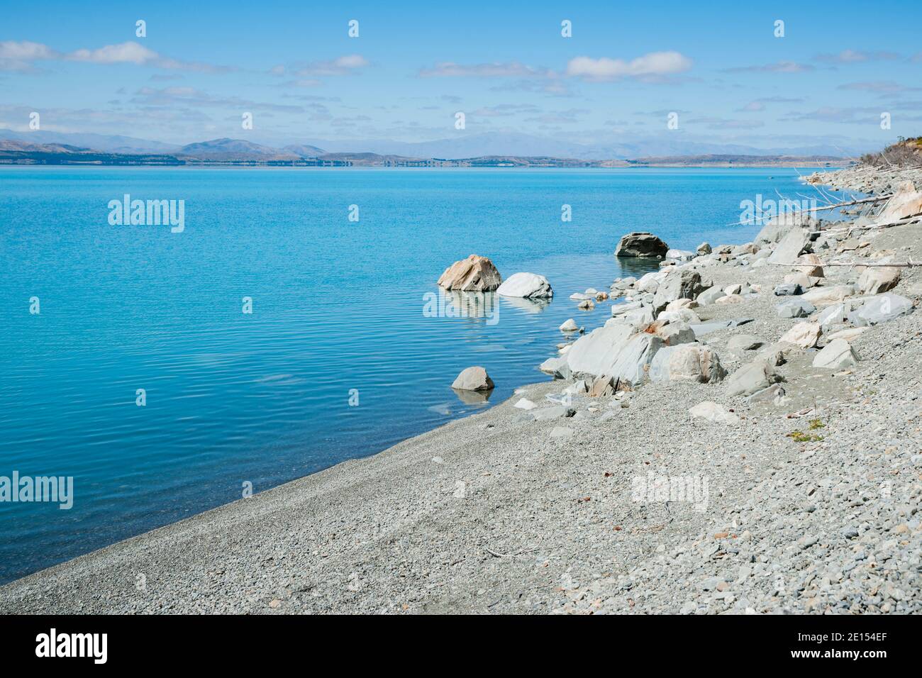 Grey stony lake edge and turquoise blue water of snow feed scenic Lake ...