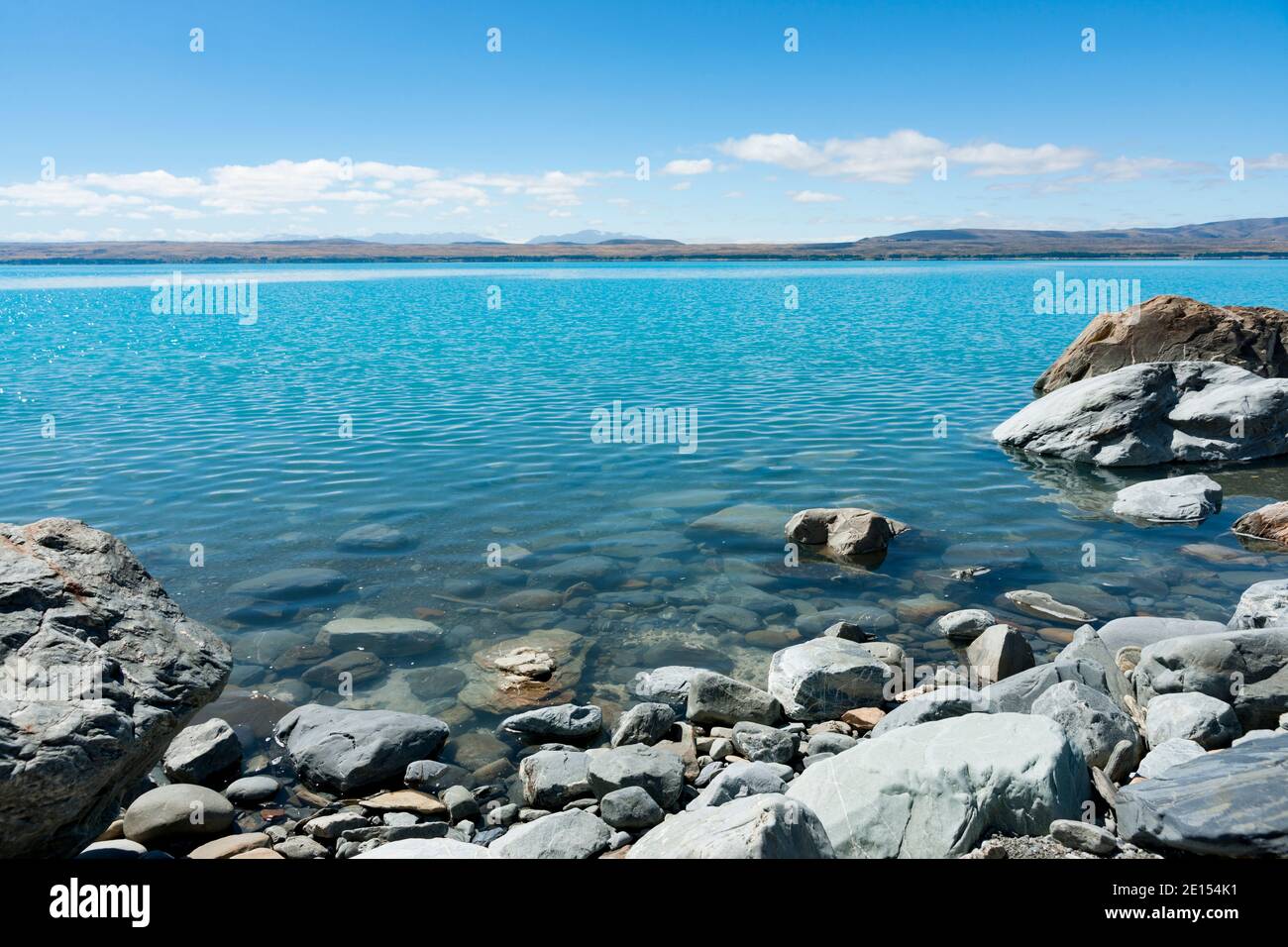 Grey stony lake edge and turquoise blue water of snow feed scenic Lake ...