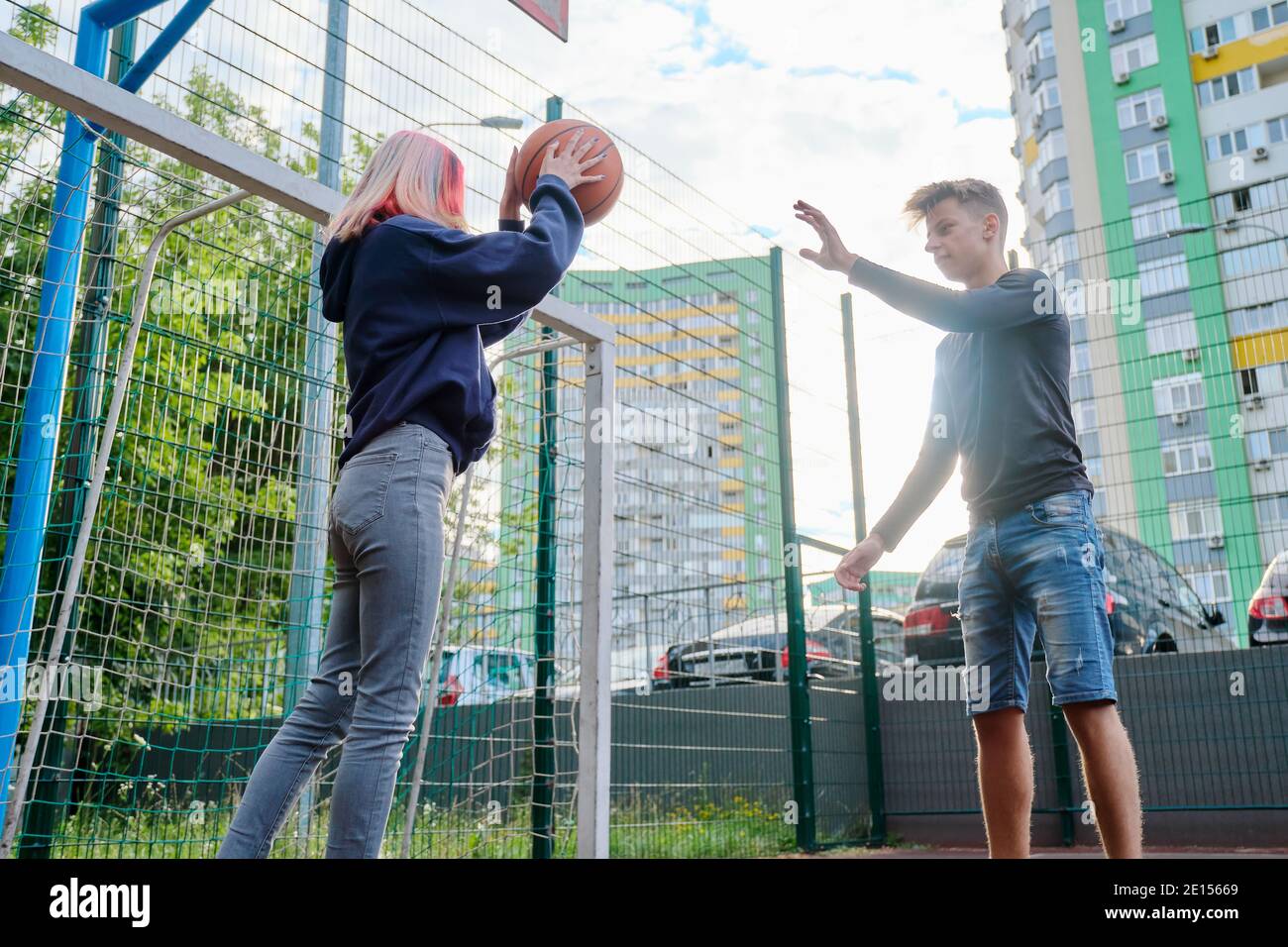 Teenagers guy and girl on an outdoor basketball court playing street ...