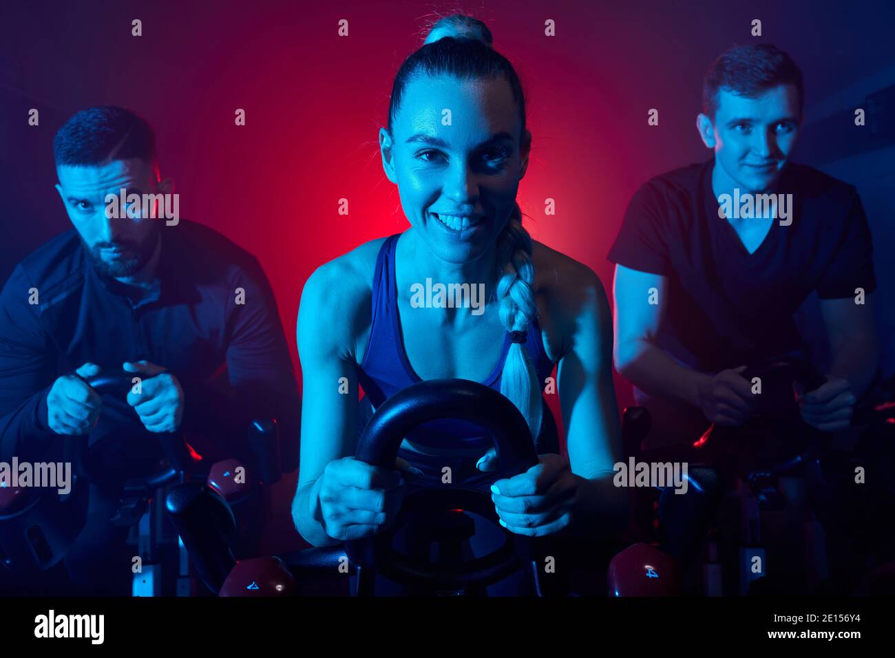 sporty people riding exercise bikes in gym, enjoying workout time, in ...