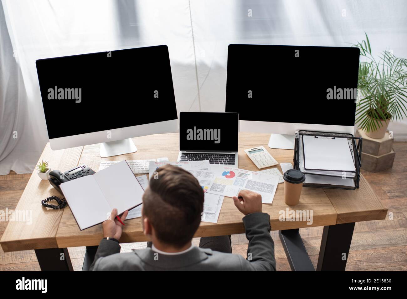 overhead view of trader holding empty notebook near monitors with blank ...