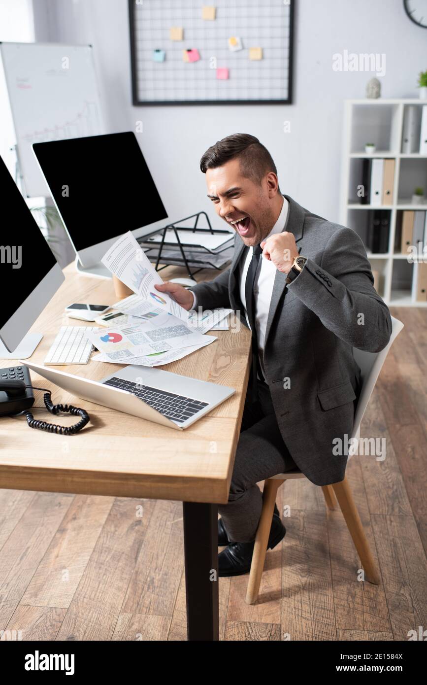 excited trader screaming and showing winner gesture at workplace Stock ...