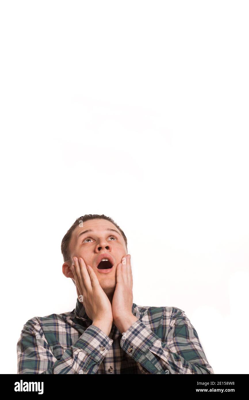 Vertical studio shot of a young man looking scared with his hands to ...