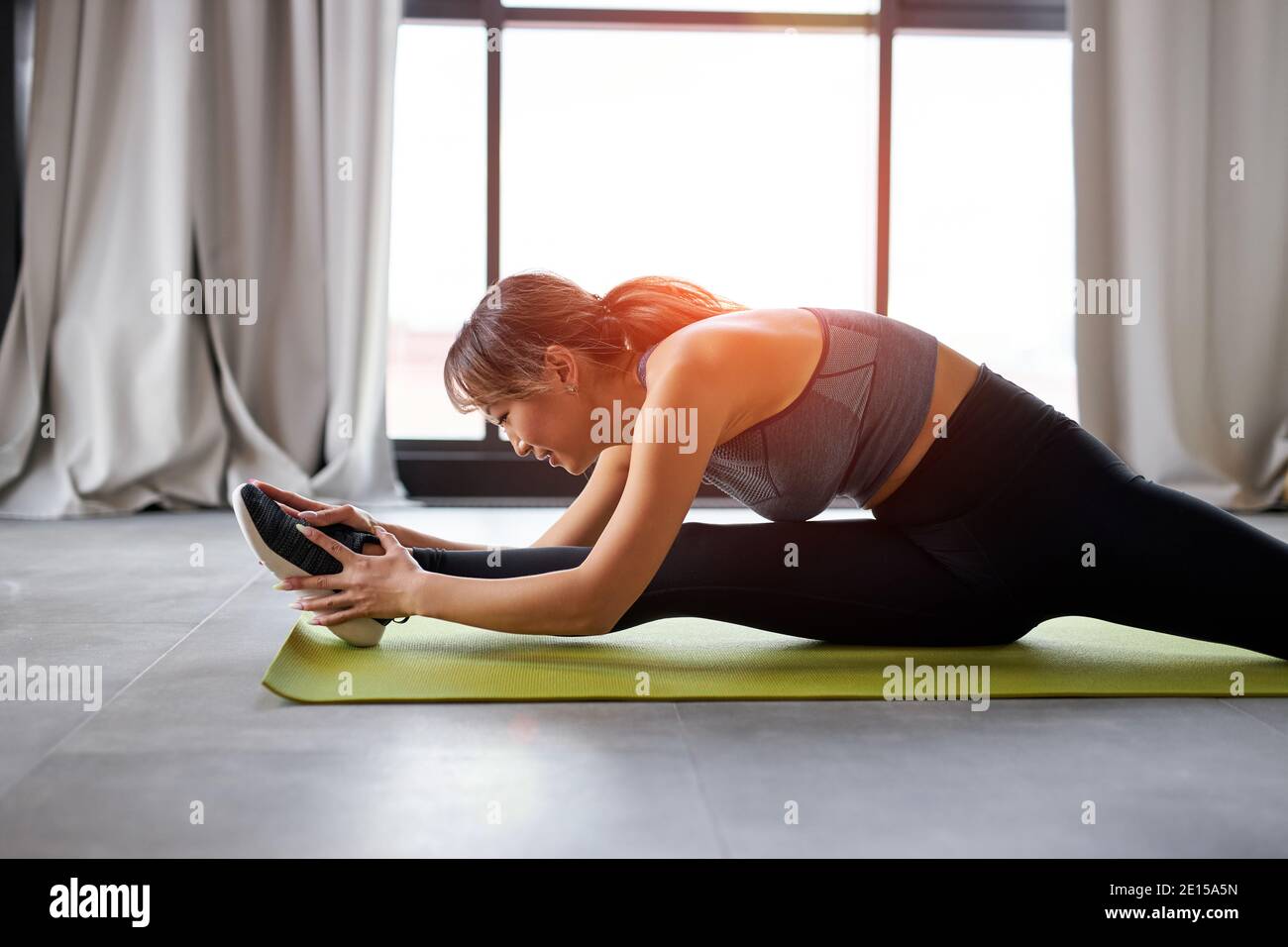 flexible female in sportive outfit stretching body, enjoy workout at ...