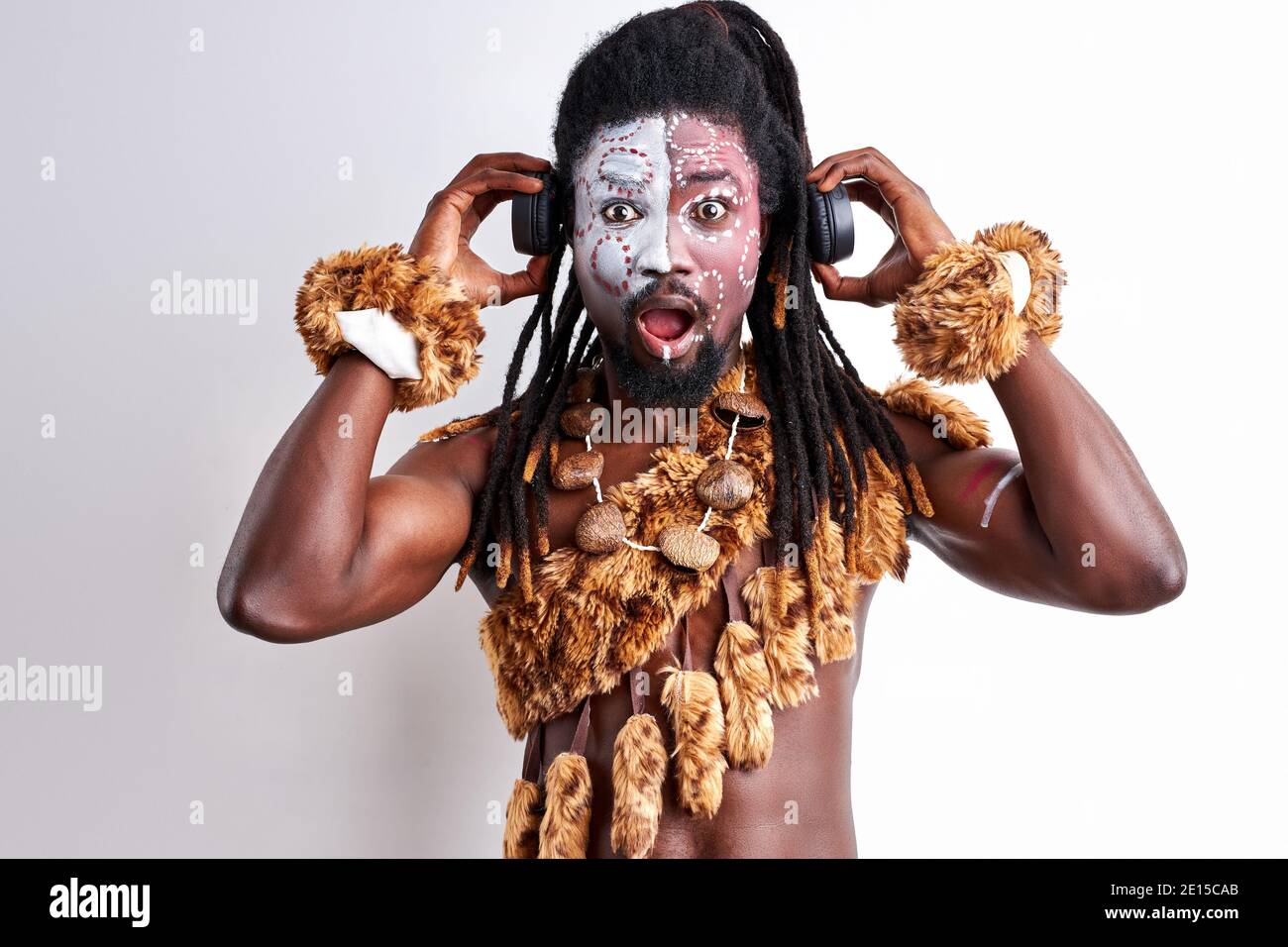 primitive male is in shock by hearing music in heaphones, he looks at ...