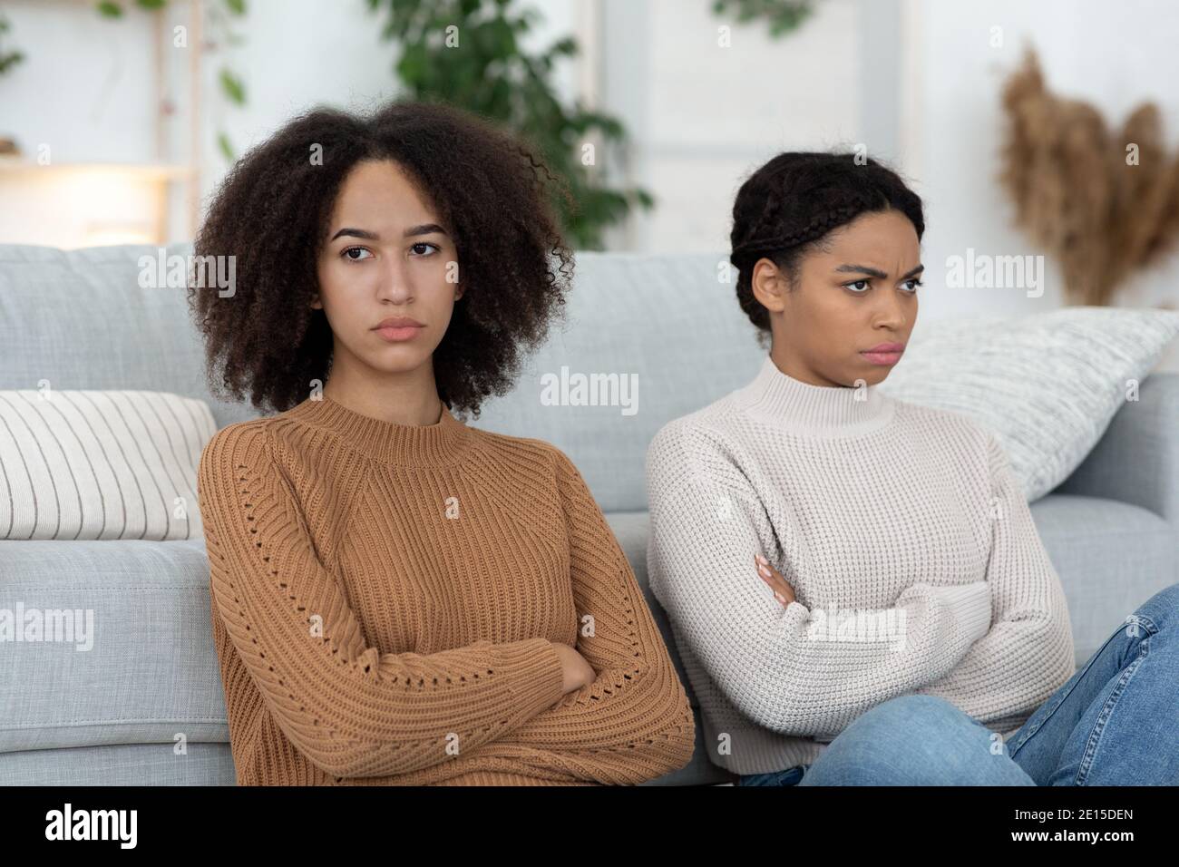 Conflict between two best friends. Women crossed arms, sitting on floor ...