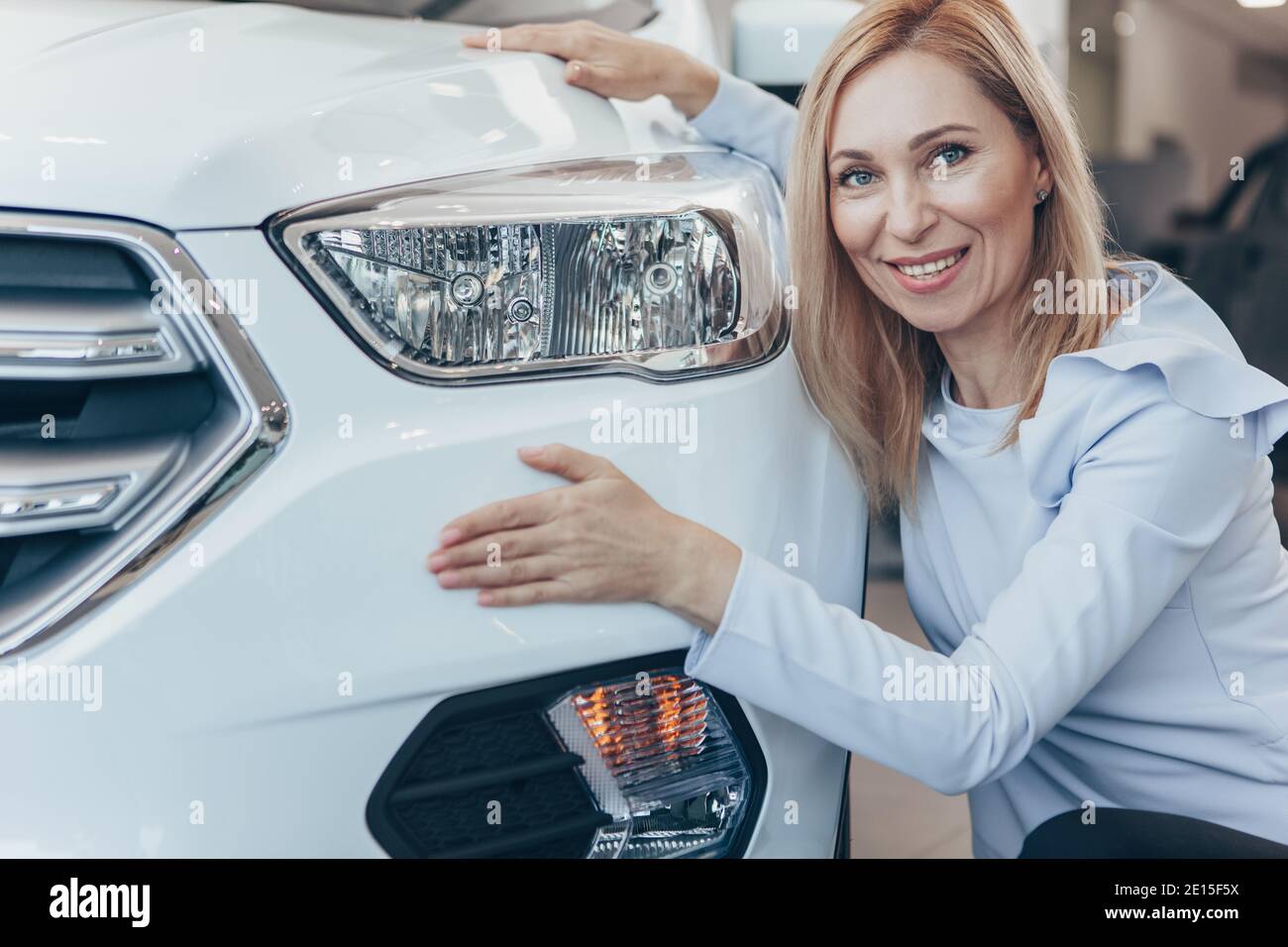 Mature businesswoman looking excited, hugging her new automobile ...