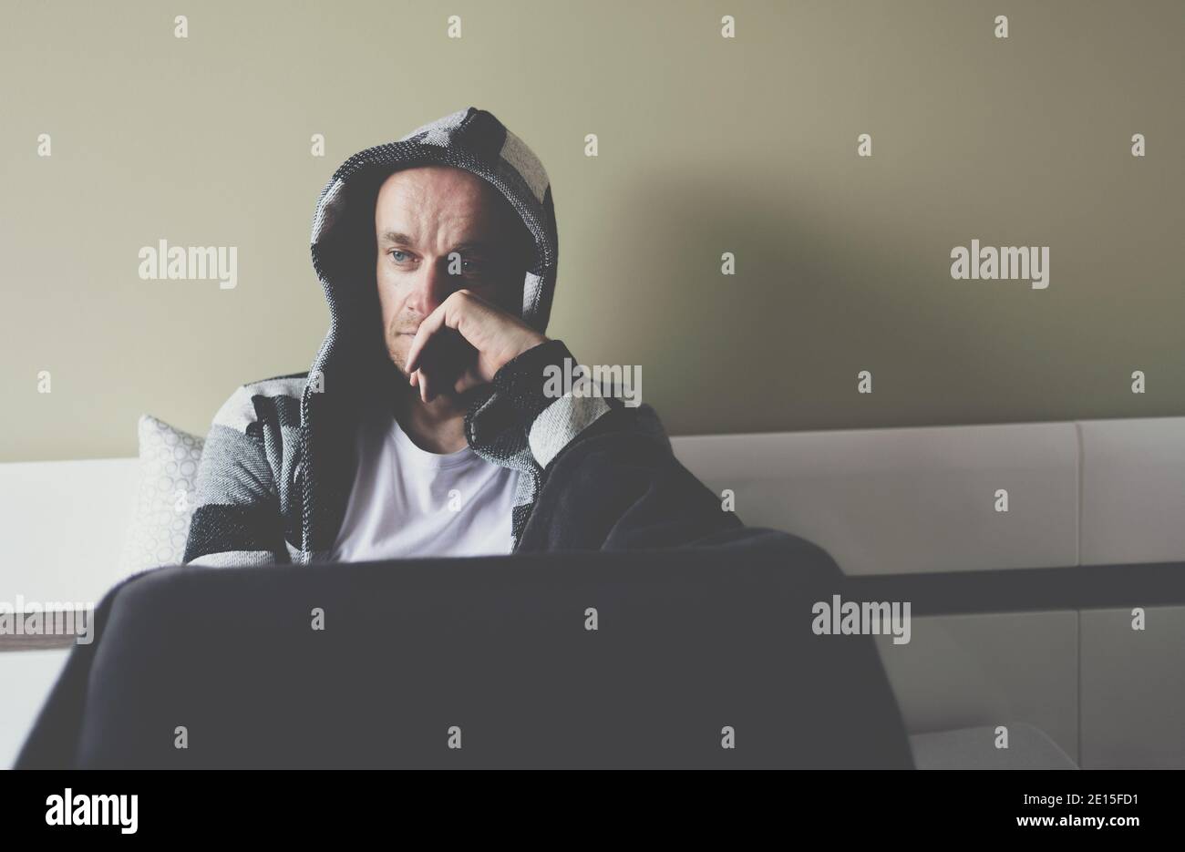 Sad pensive man sitting on the bed in the bedroom Stock Photo - Alamy