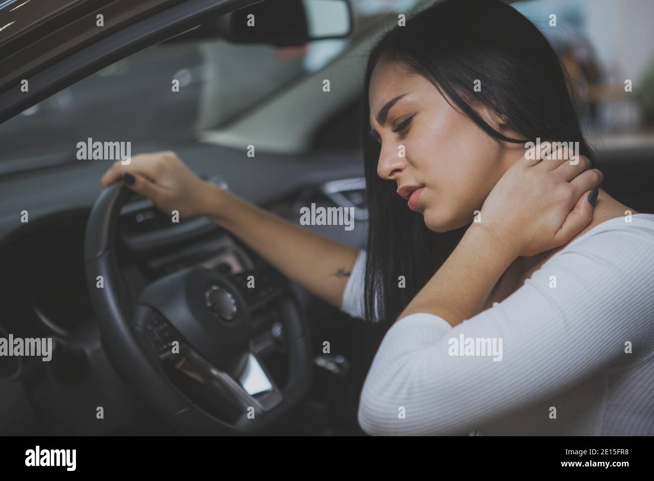 Beautiful young woman rubbing her neck, feeling sore after long drive ...