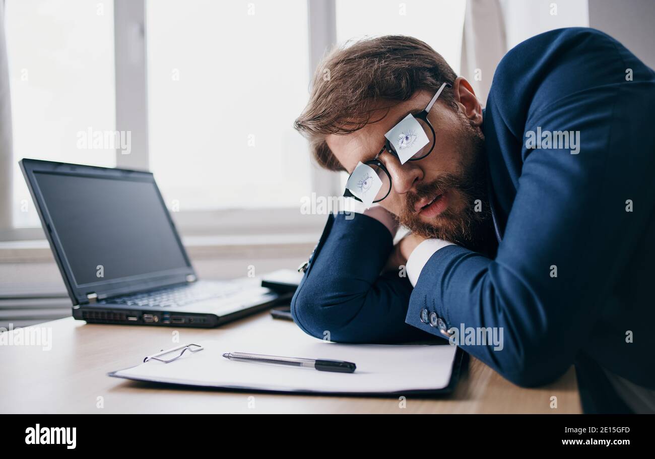 Business man sleeping at work wearing glasses with sheets of paper ...