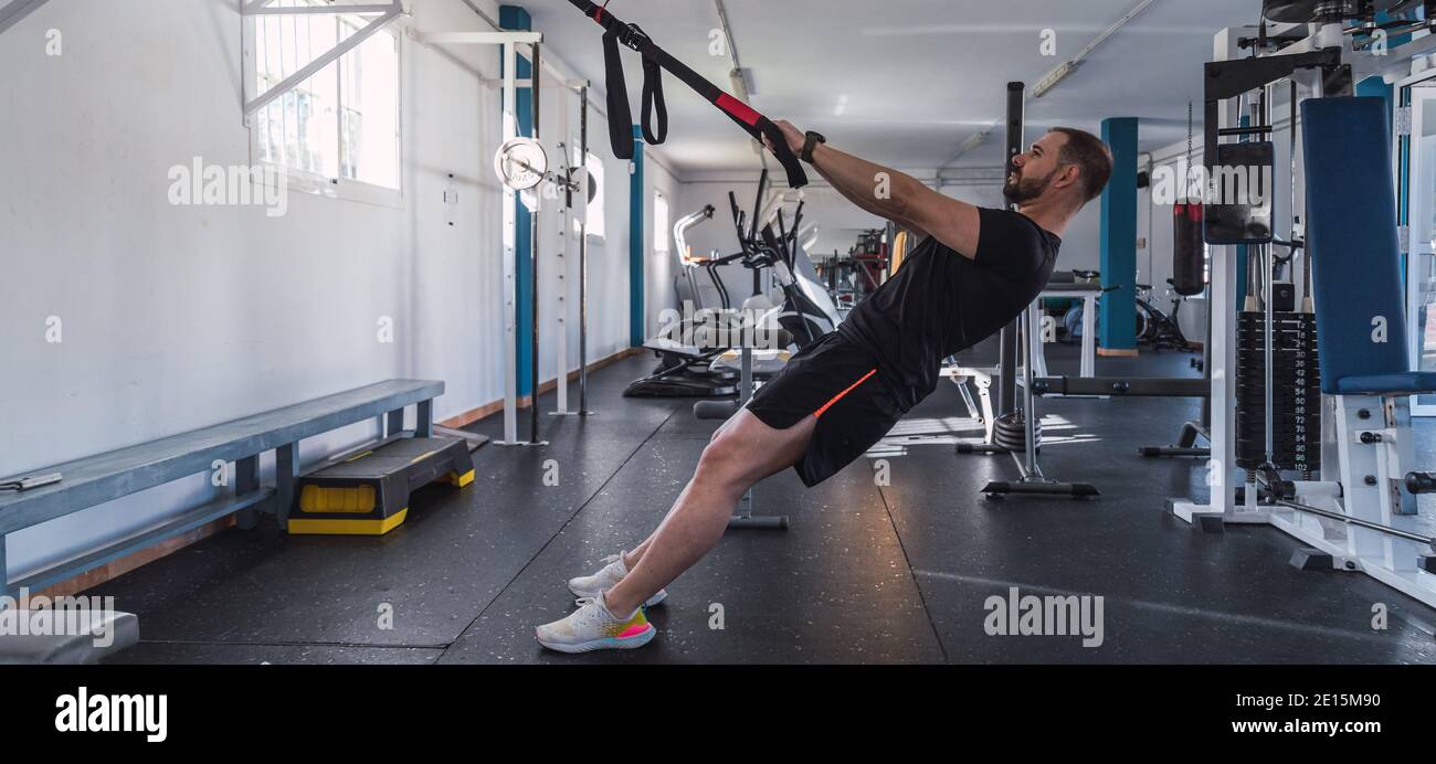 Young man doing TRX exercises at the gym. TRX training Stock Photo - Alamy