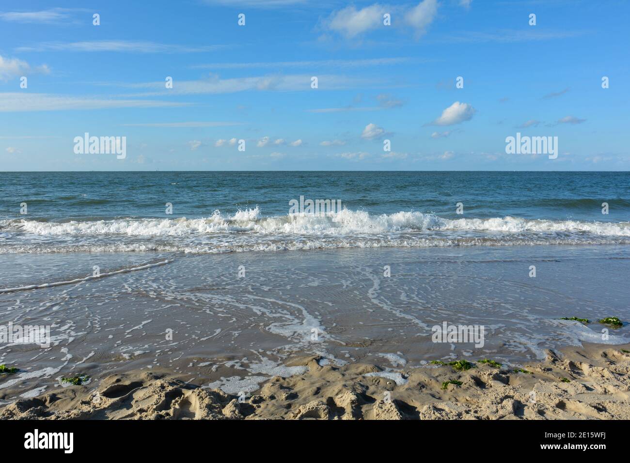 Waves on sand beach with blue sky Stock Photo - Alamy