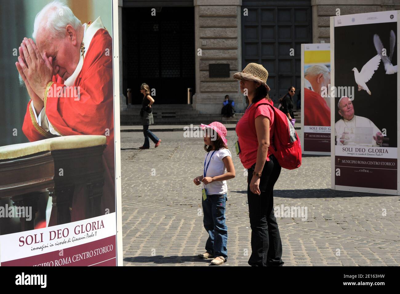 People walk past placards showing pictures of late pope John Paul II ...