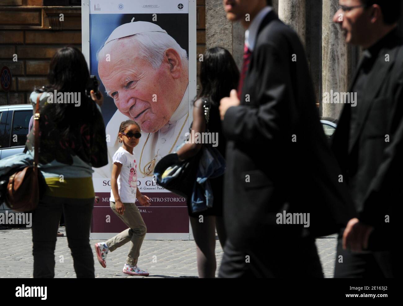 People walk past placards showing pictures of late pope John Paul II ...