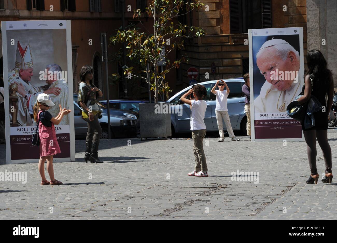 People walk past placards showing pictures of late pope John Paul II ...