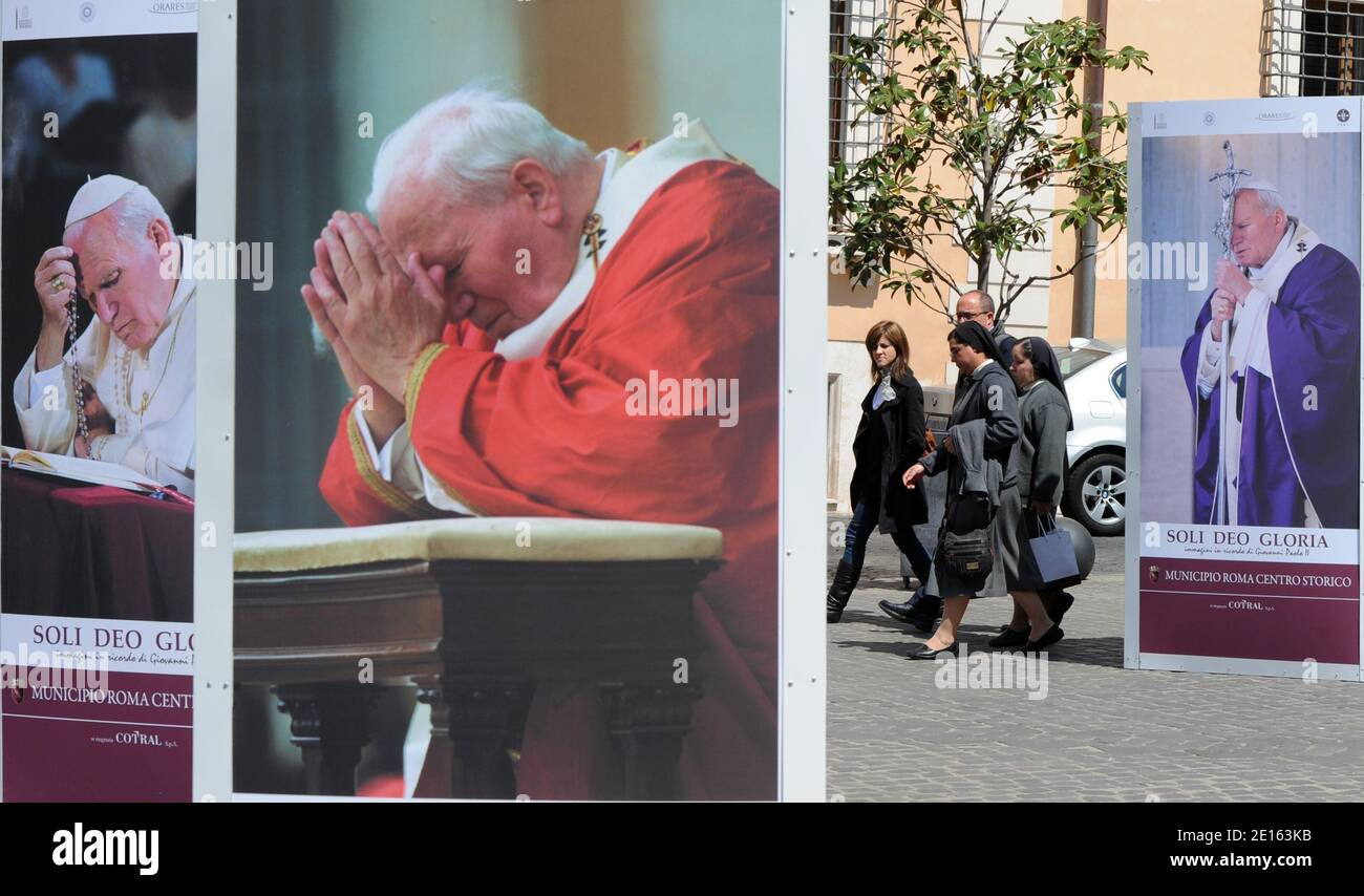 People walk past placards showing pictures of late pope John Paul II ...