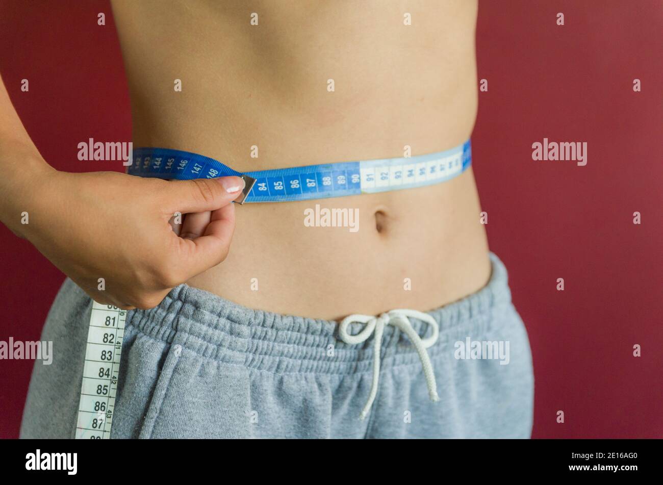 Skinny young woman measuring her slim waist with a measuring tape Stock ...