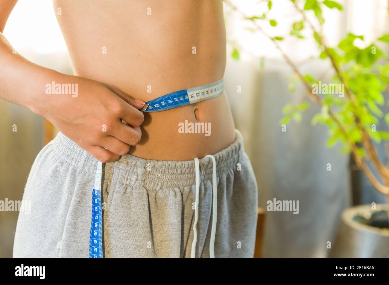 Skinny young woman measuring her slim waist with a measuring tape Stock ...