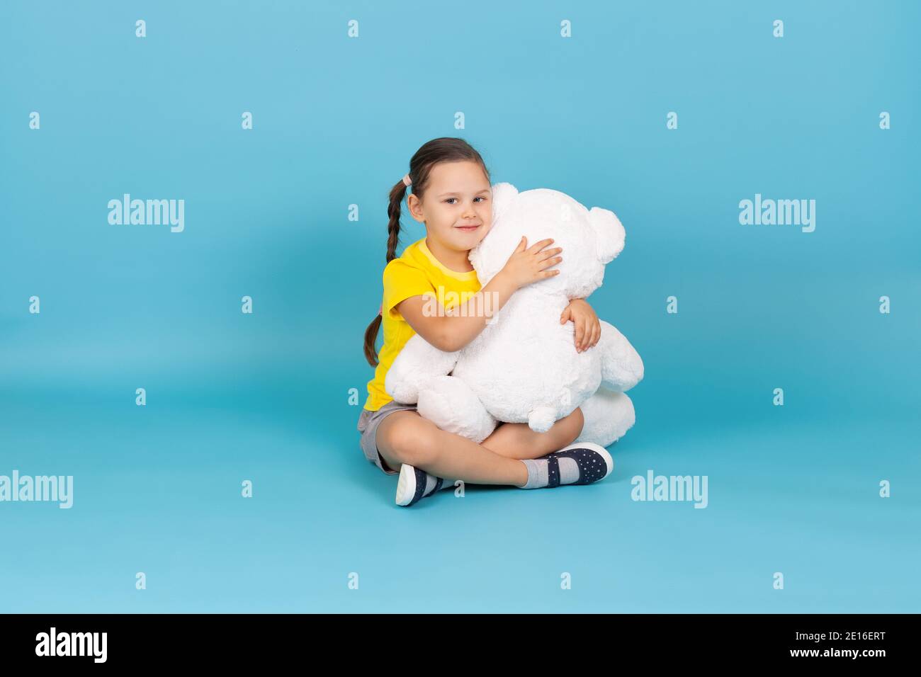happy contented girl with pigtails sitting cross-legged on the floor ...