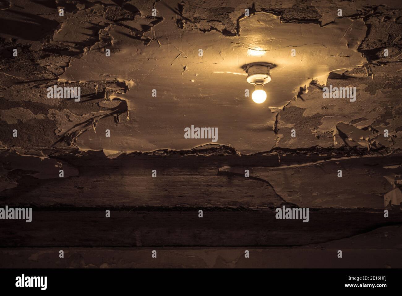 Illuminated bare light bulb in an abandoned building with cracked ...