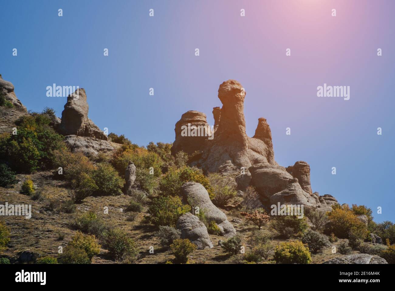 Stone hills and mountains with green trees and bushes against the blue ...