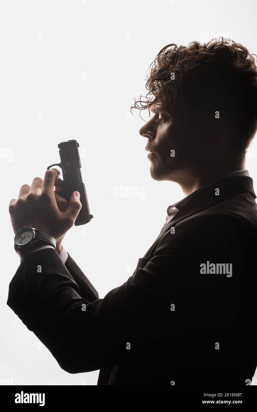 side view of curly man in suit holding gun isolated on white Stock ...